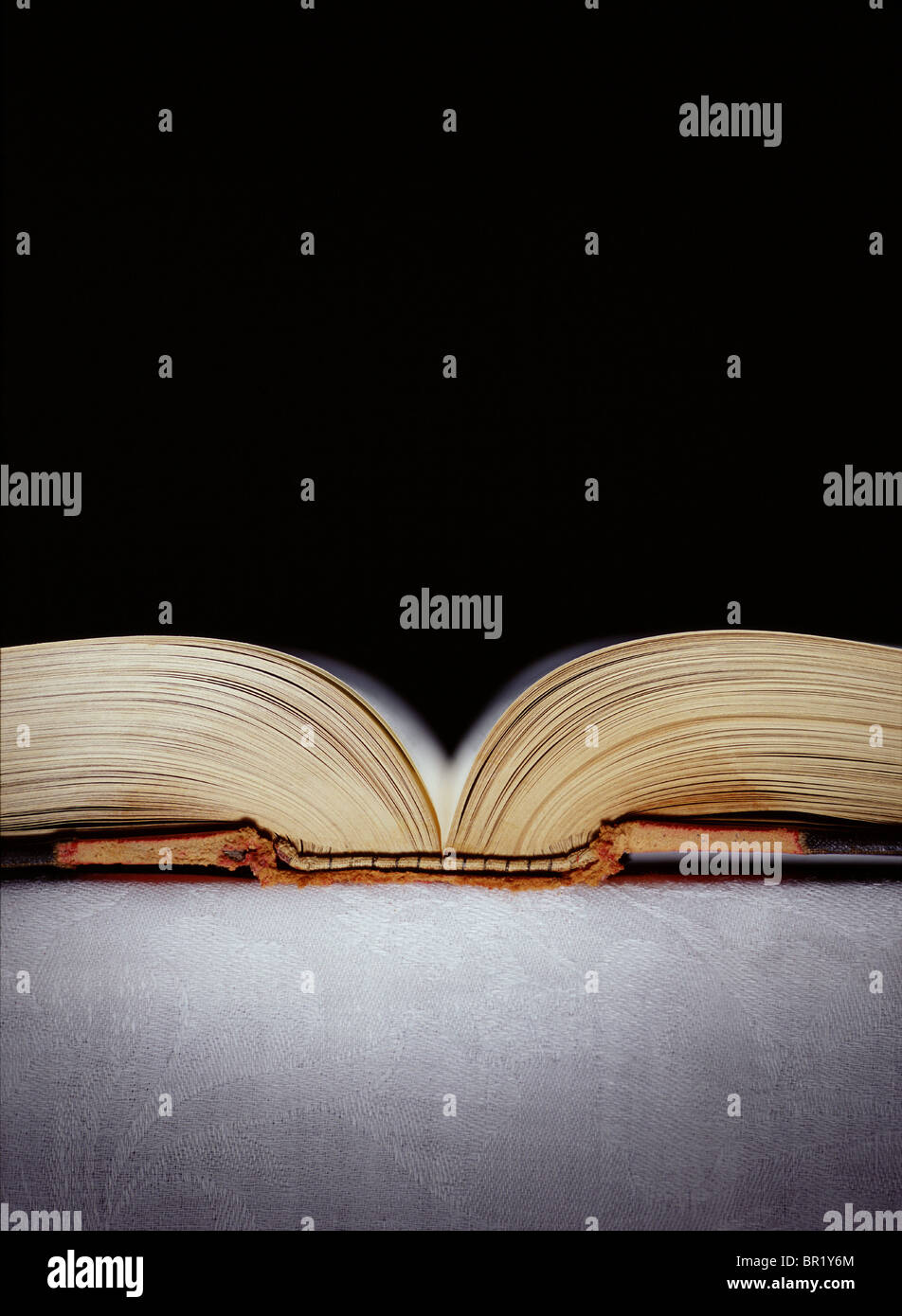 Book laying open on a table surface with black background Stock Photo ...