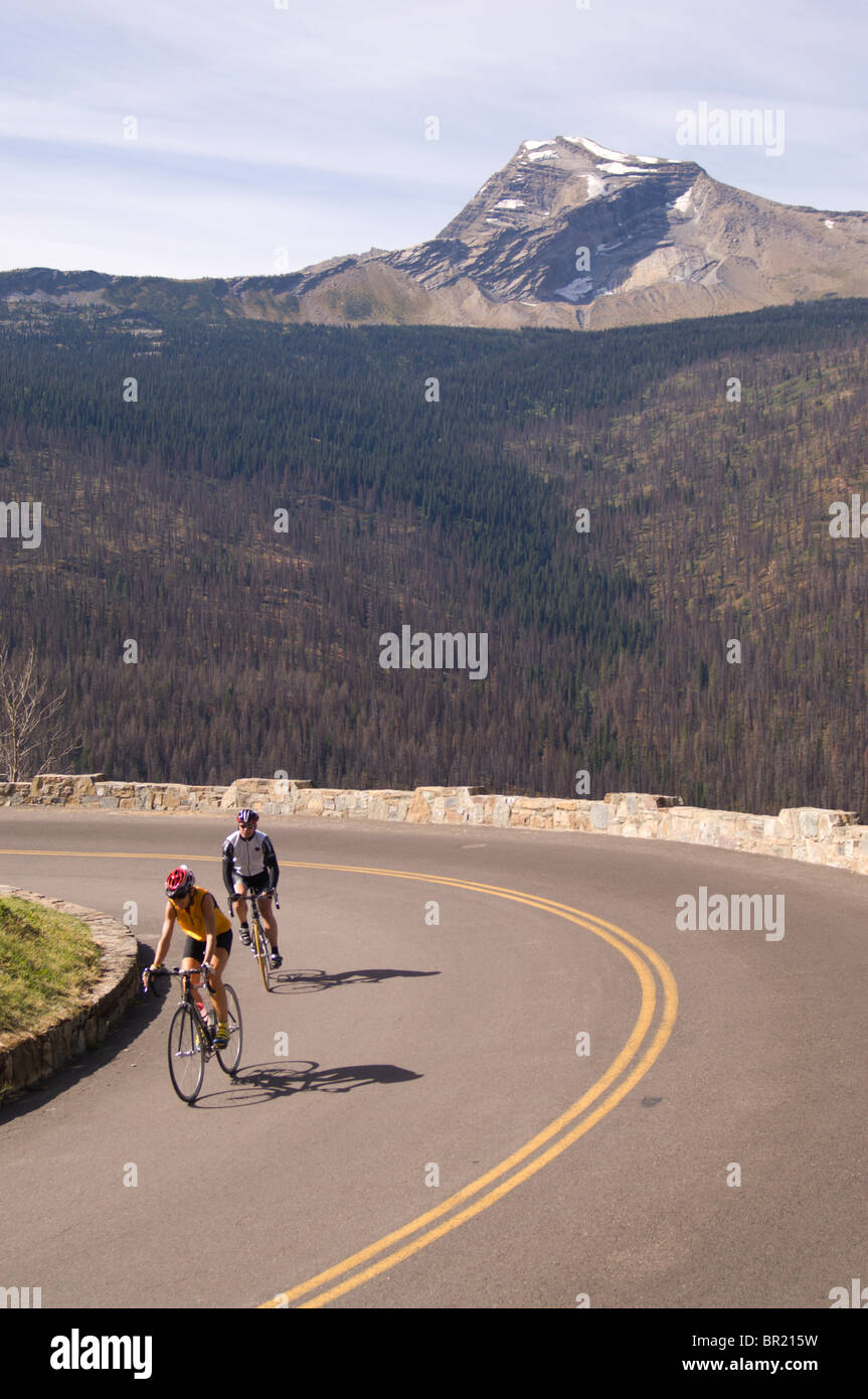 Two cyclists climb a hill with a mountain in the distance Stock Photo ...