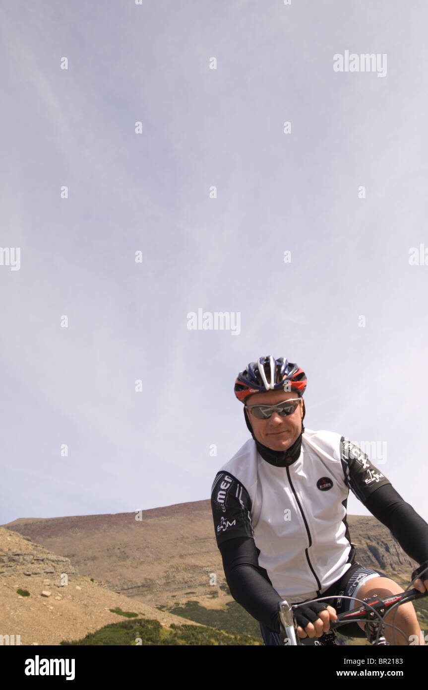 Cyclists climb a hill with a mountain in the distance Stock Photo - Alamy