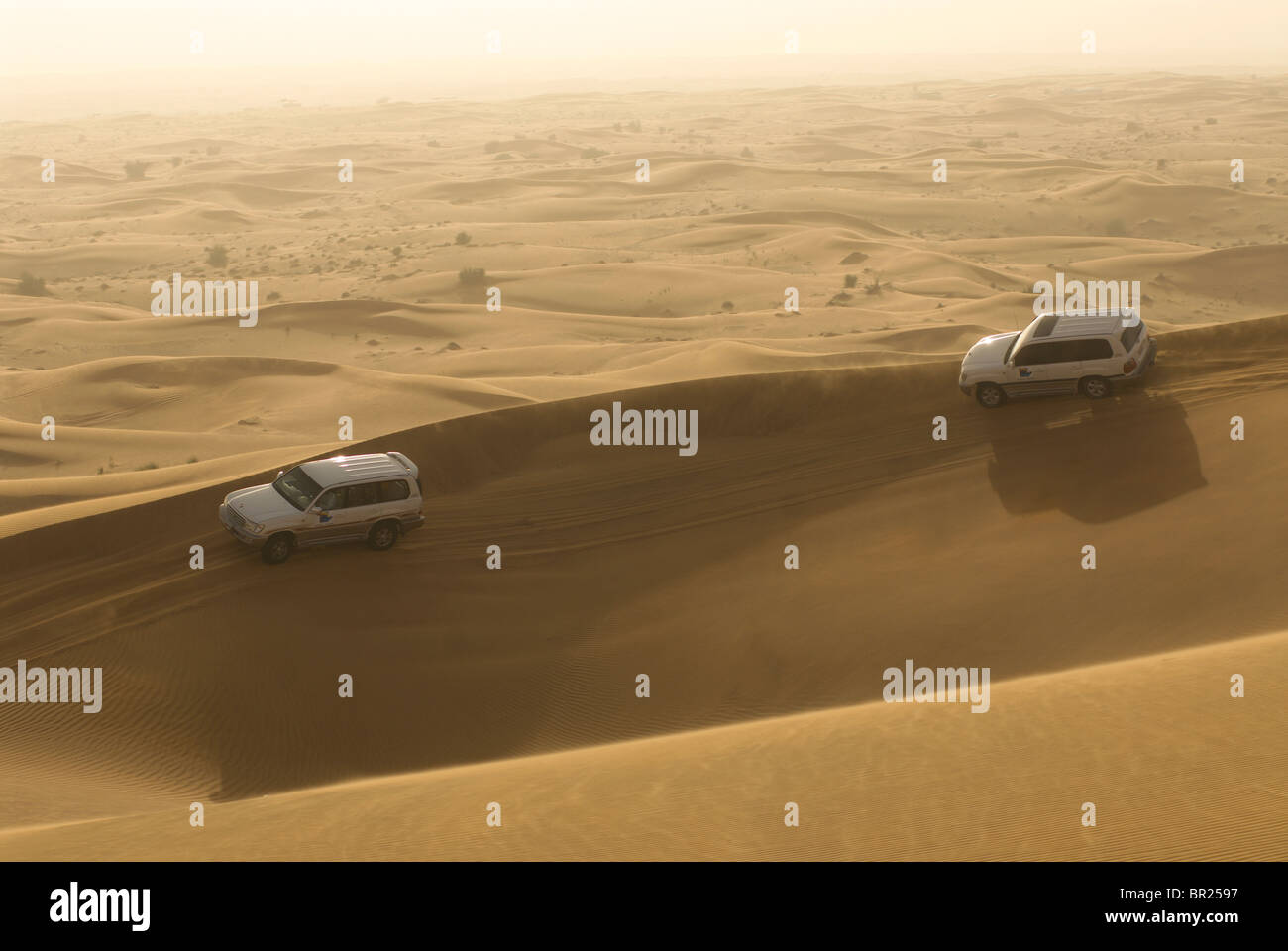 Four wheel drive vehicles negotiate sand dunes during a desert driving ...