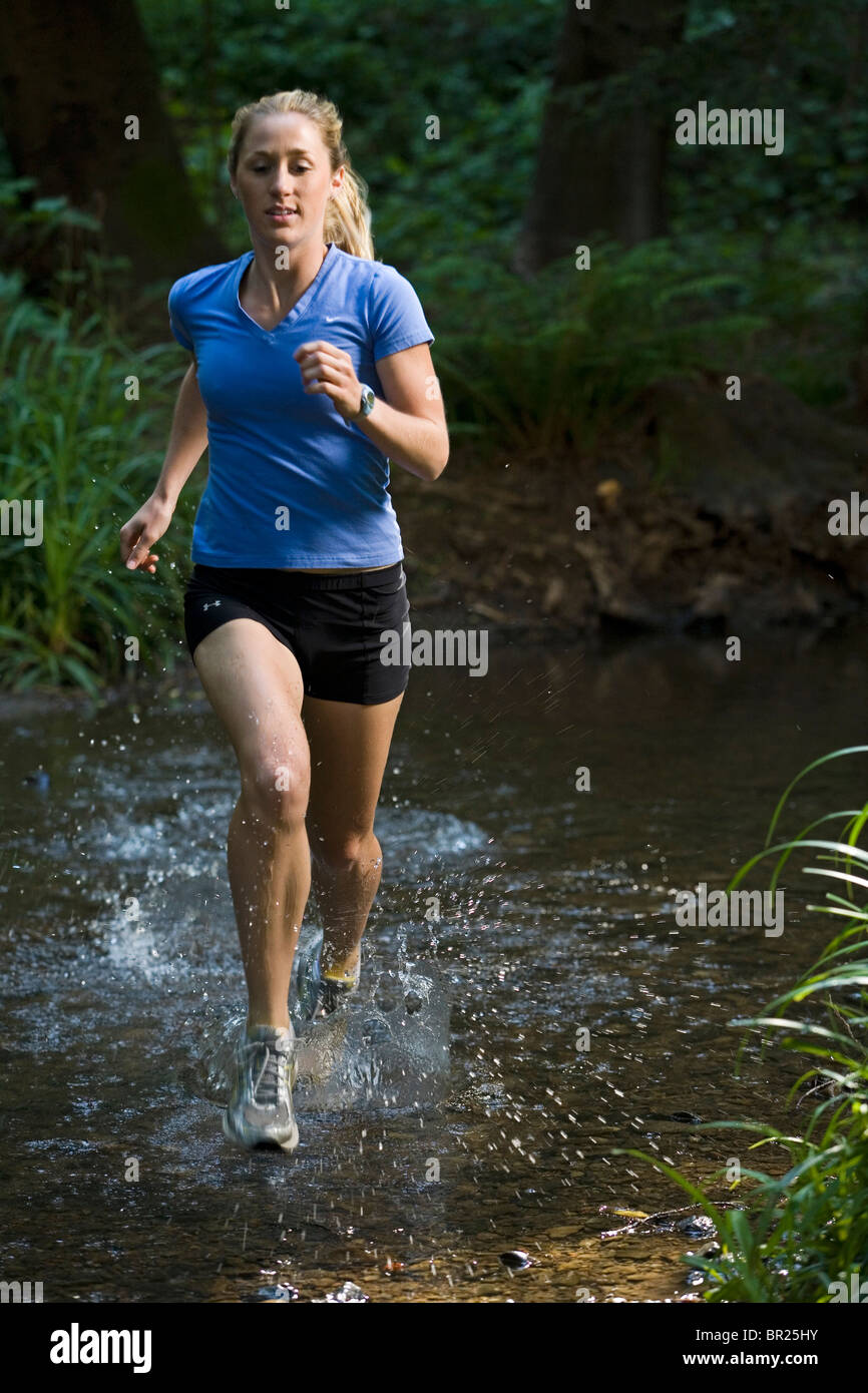 In the darkness of a redwood forest, a runner crosses a stream Stock ...