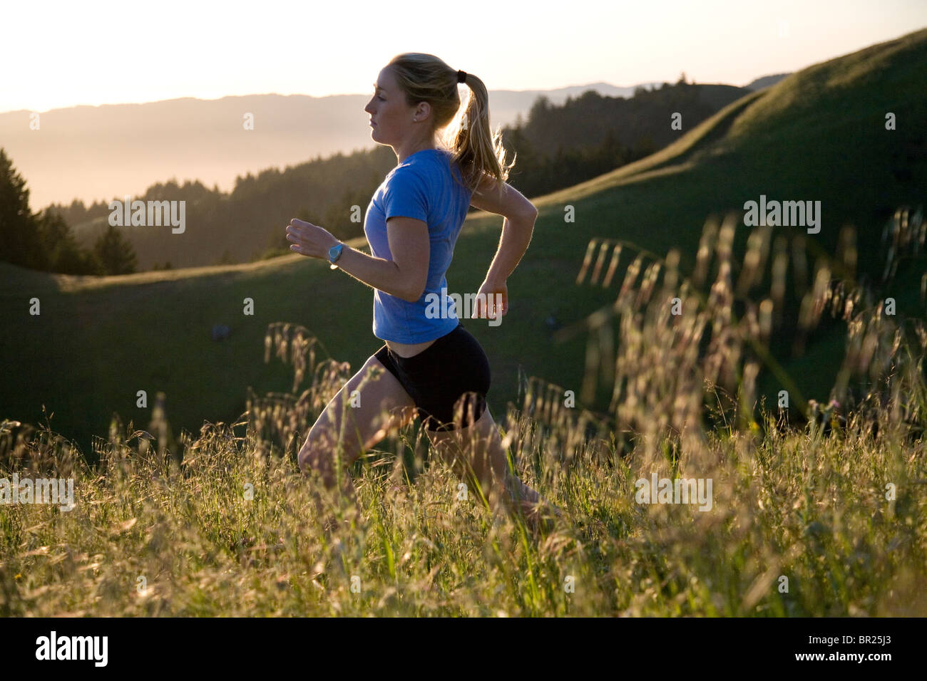 As sunset nears, a runner follows a tiny, single-track trail along the ...