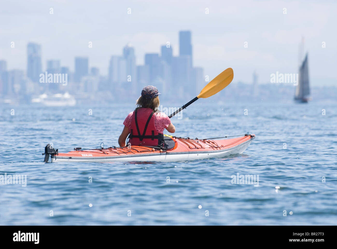 A woman kayaking in Puget Sound on June 9, 2007 with Seattle in the ...