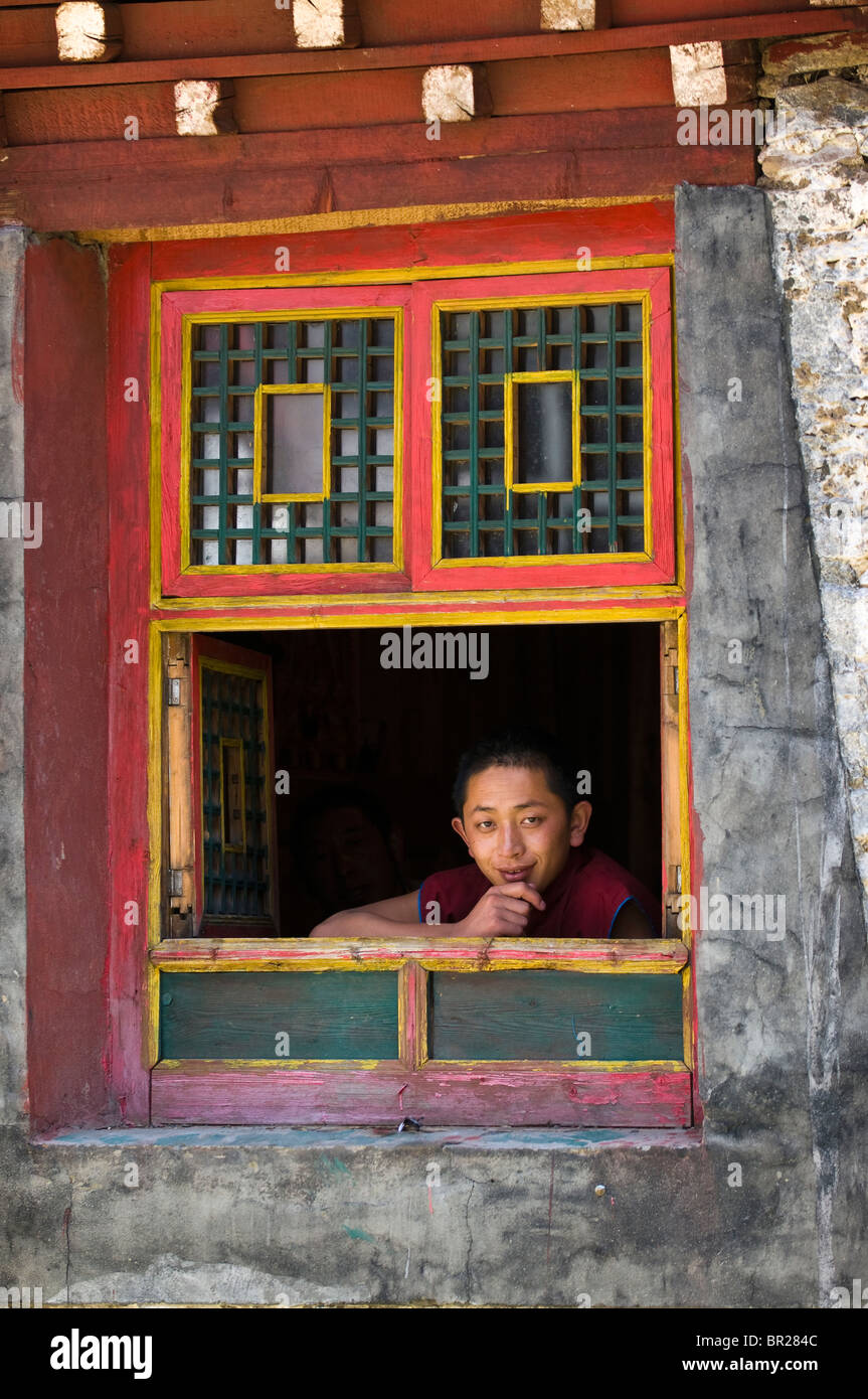 Young Tibetan Buddhist monk peers from window of living quarters, Juli ...