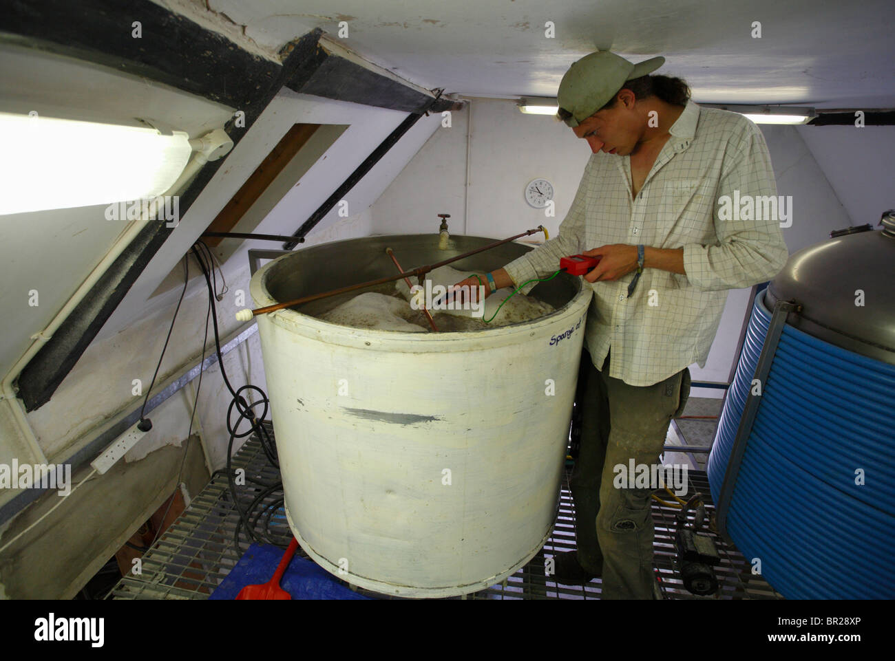 A brewer testing the water temperature at the sparge arm during ...