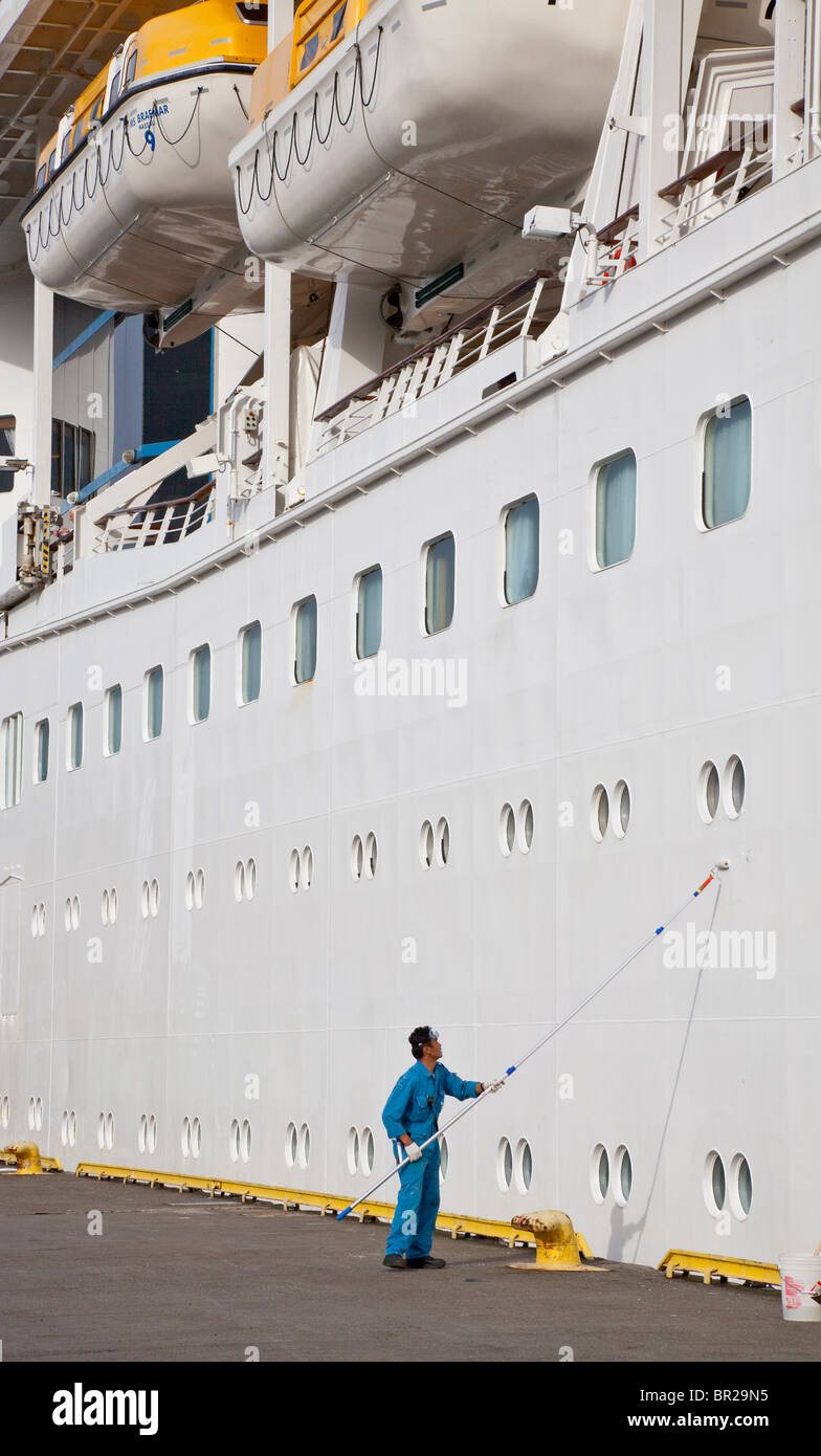 Cruise ship maintenance, contractor spot painting the exterior hull ...