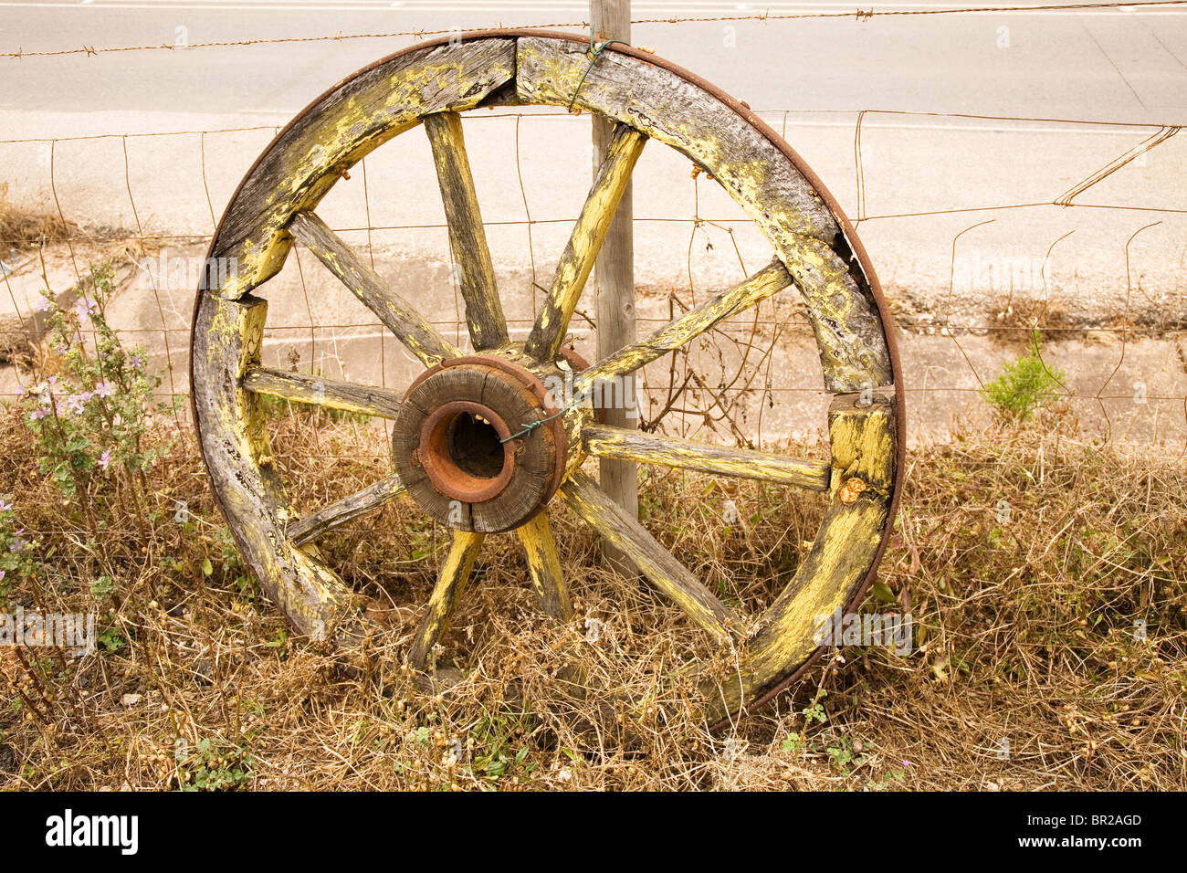 A wooden wagon wheel stands by a fence Stock Photo - Alamy