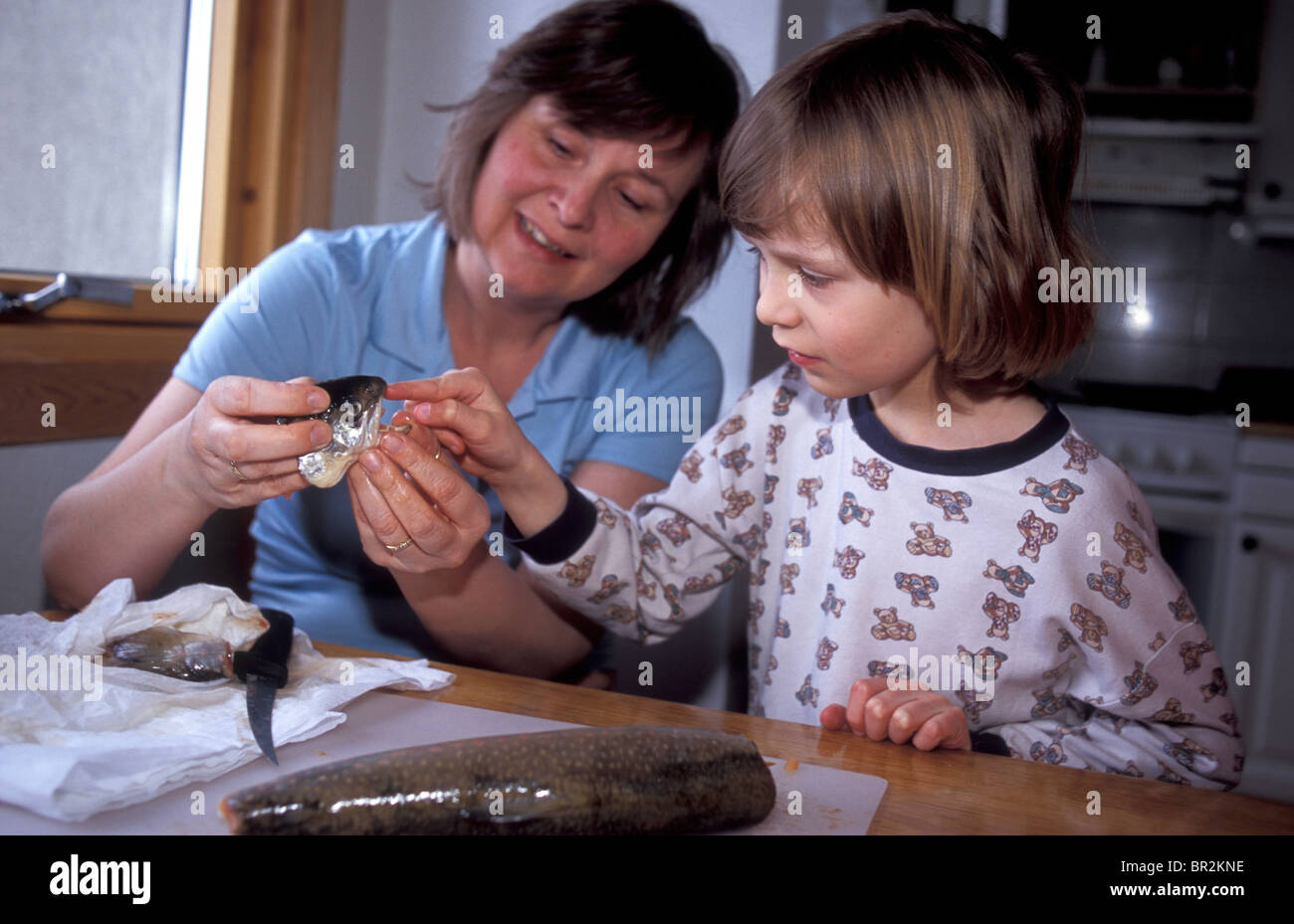 Mother showing how to prepare a fish Stock Photo - Alamy