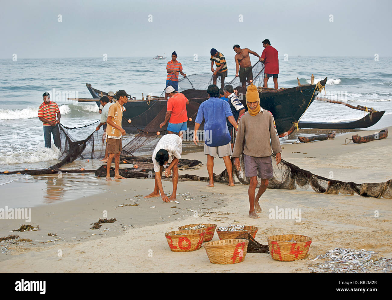 Indian fishermen repairing their nets on the beach, Goa, India Stock ...