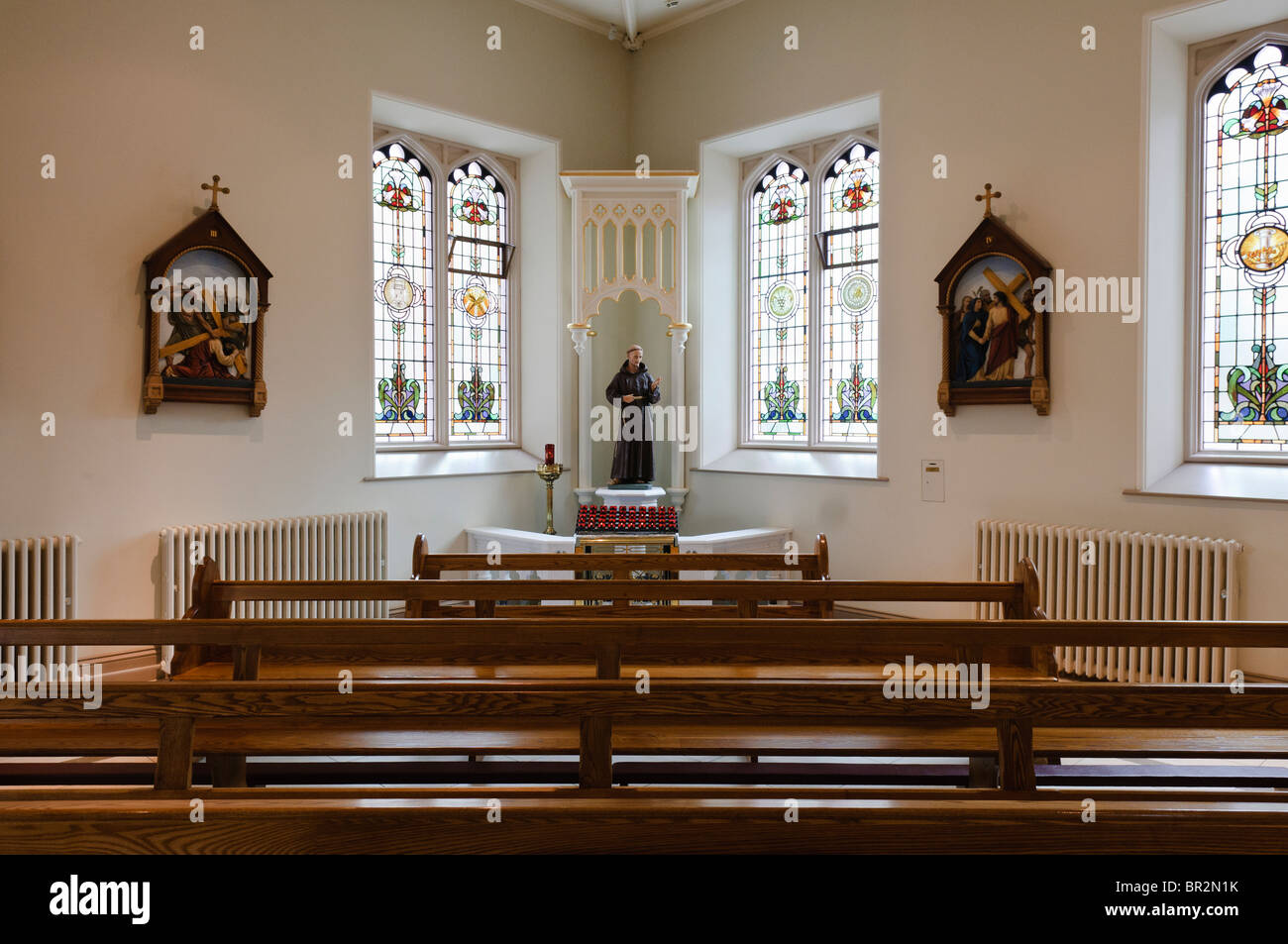Pews, statue of St Francis of Assisi and stations of the cross in a ...
