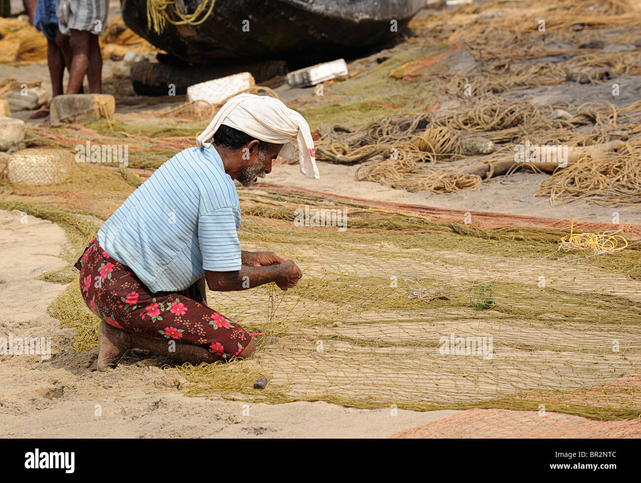 Fisherman repairing fishing net on the beach, Kovalam, Kerala, India ...