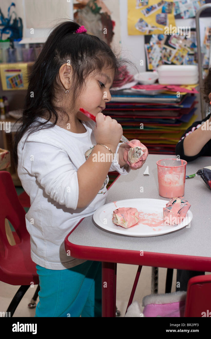 4 year old preschool girl working on an art project in the classroom ...