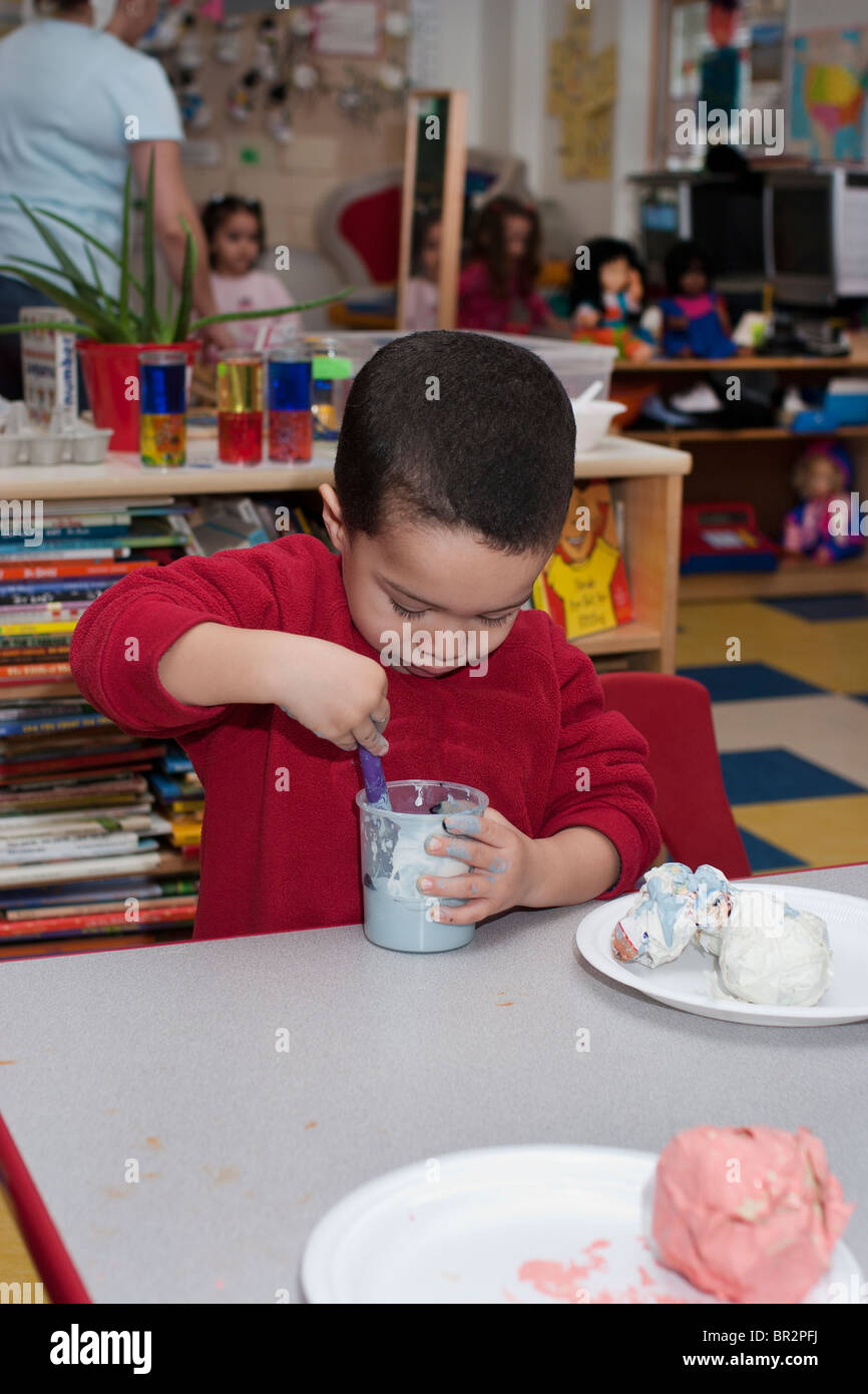 4 year old preschool boy working on an art project in the classroom ...