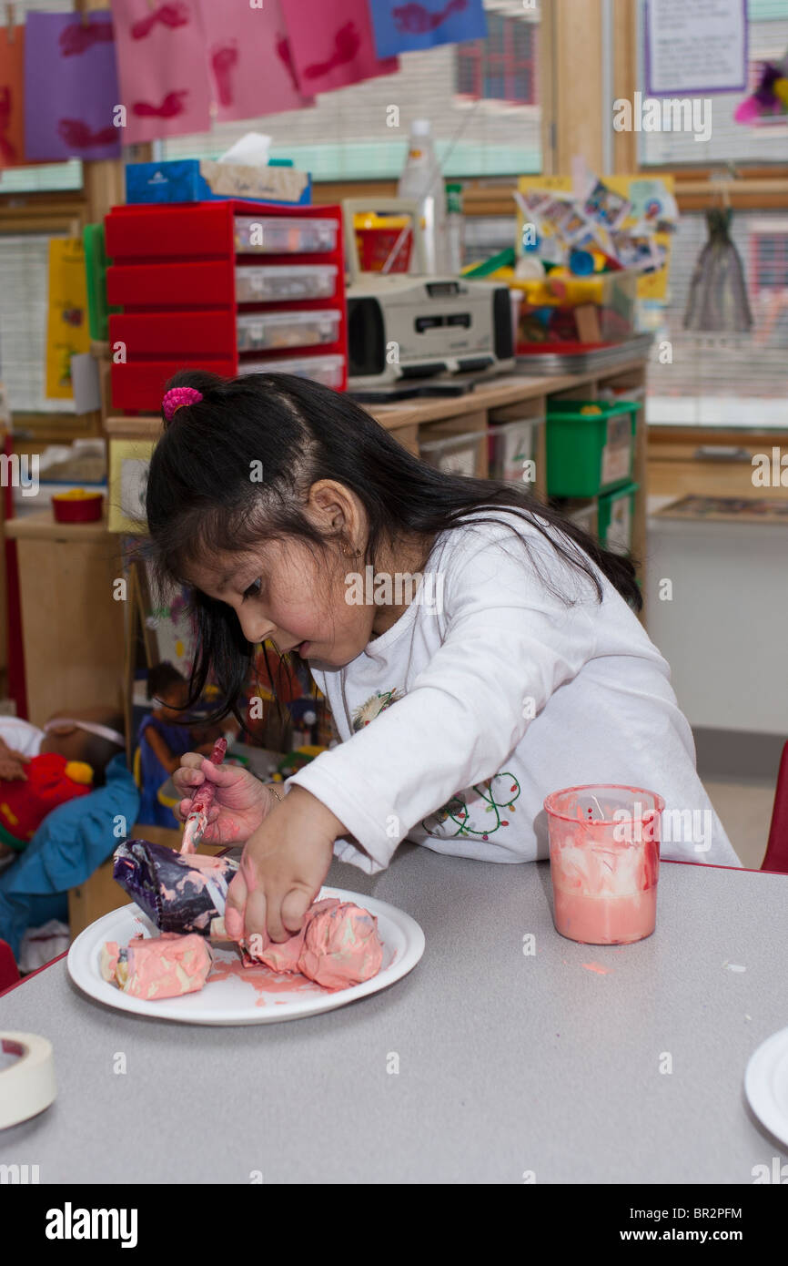4 year old preschool girl working on an art project in the classroom ...