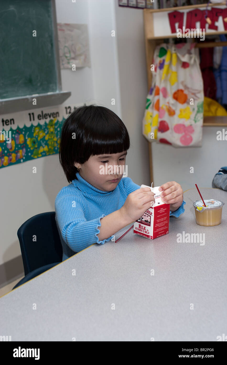 4 year old preschool girl opening a container of milk sitting at a ...