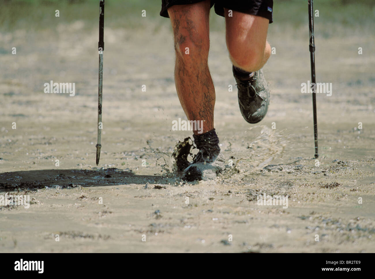 Hiker's feet splashing through grey mud Stock Photo - Alamy