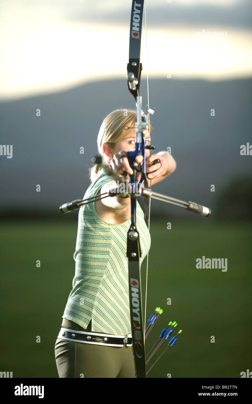 Attractive female using a bow and arrow/archery Stock Photo - Alamy