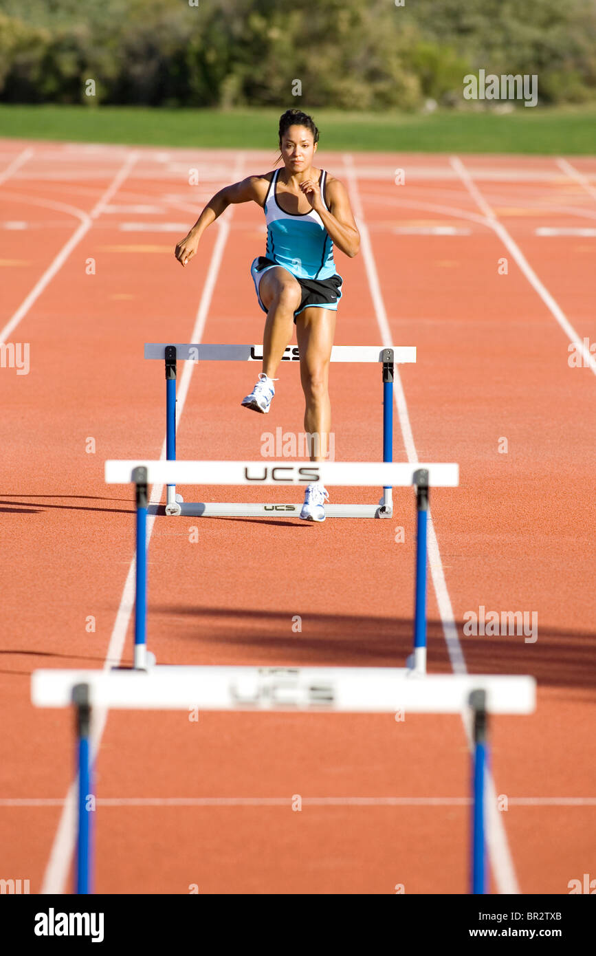 Attractive woman running hurdles on a track Stock Photo - Alamy