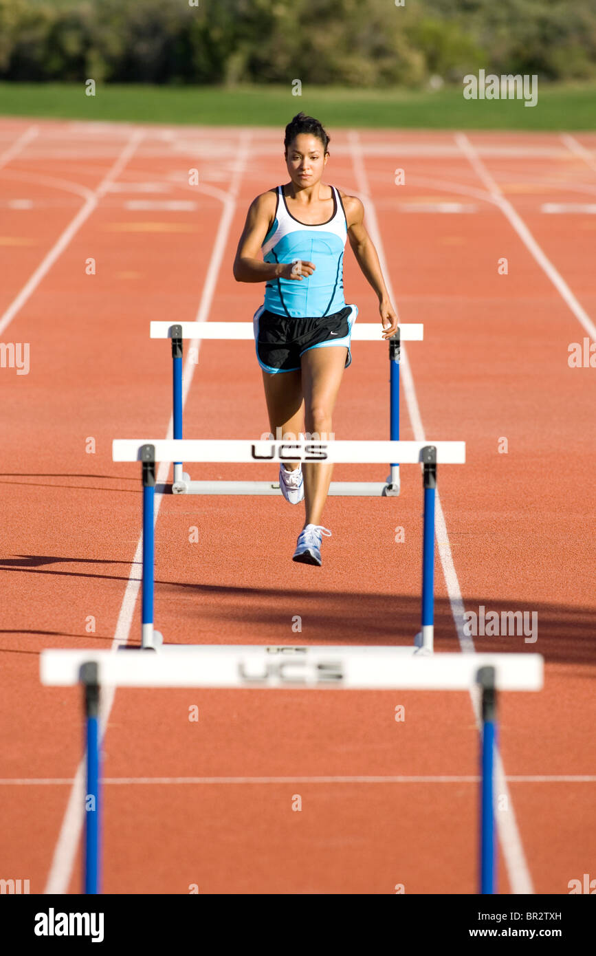 Attractive woman running hurdles on a track Stock Photo - Alamy
