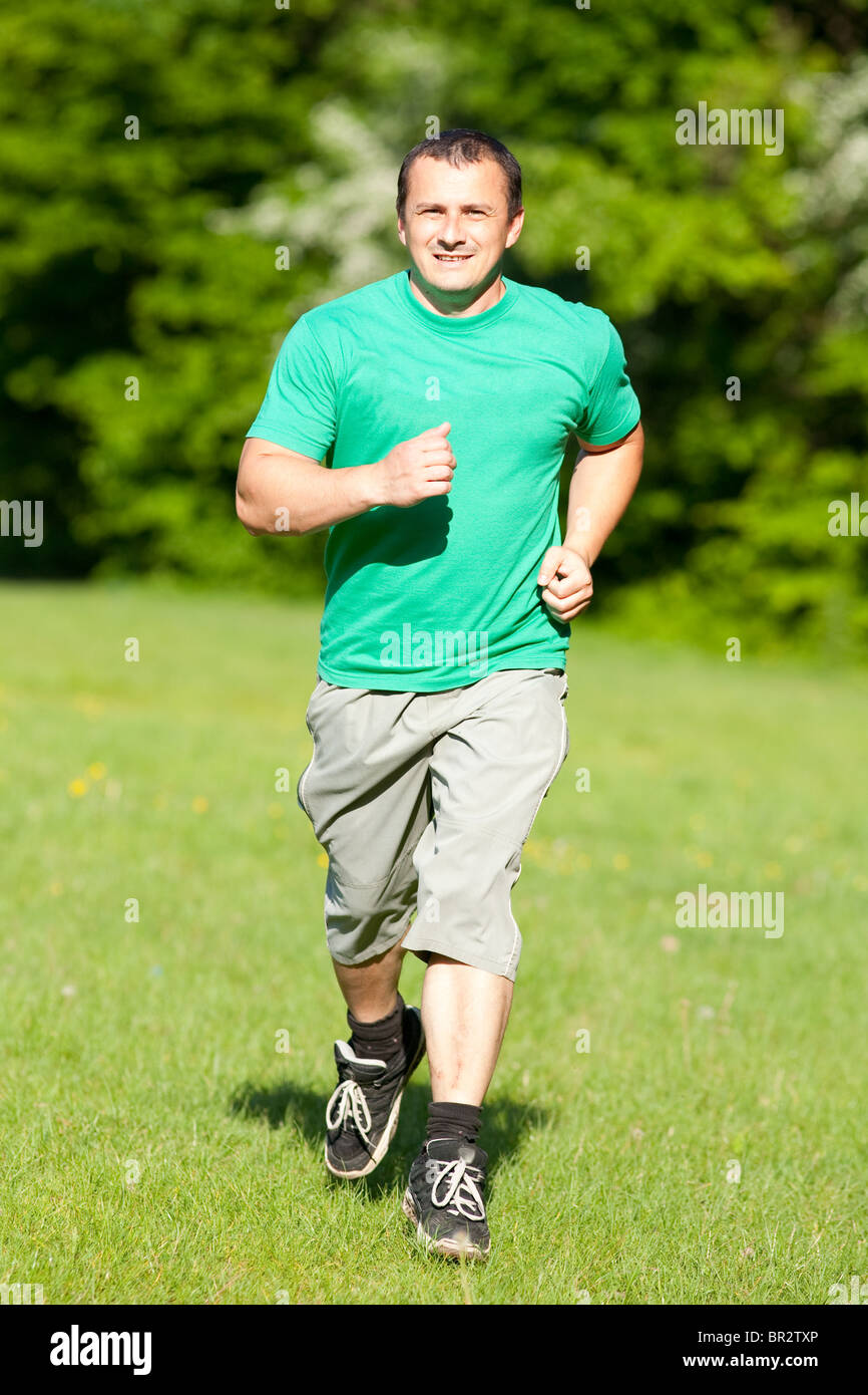Young man running outdoors on a meadow Stock Photo - Alamy