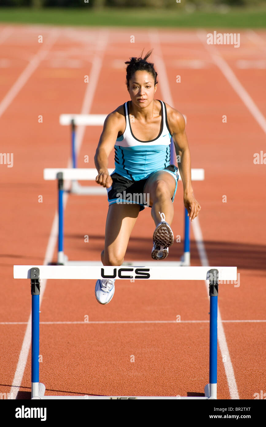 Attractive woman running hurdles on a track Stock Photo - Alamy