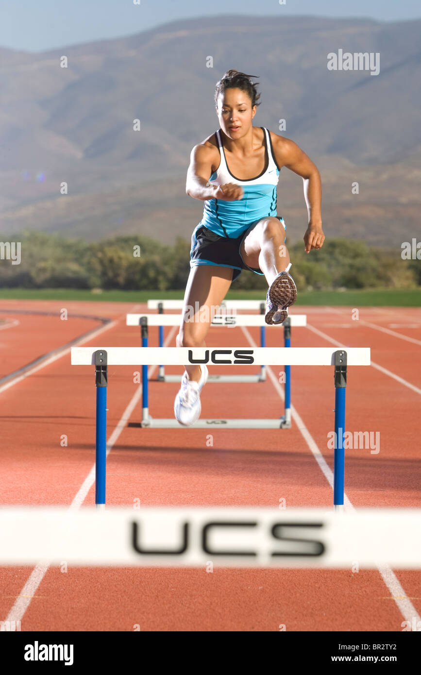 Attractive woman running hurdles on a track Stock Photo - Alamy