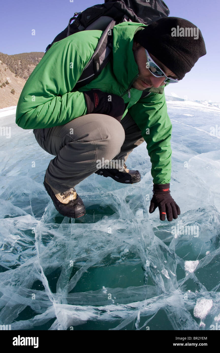 A hiker examines the frozen Lake Baikal during the winter in Siberia ...