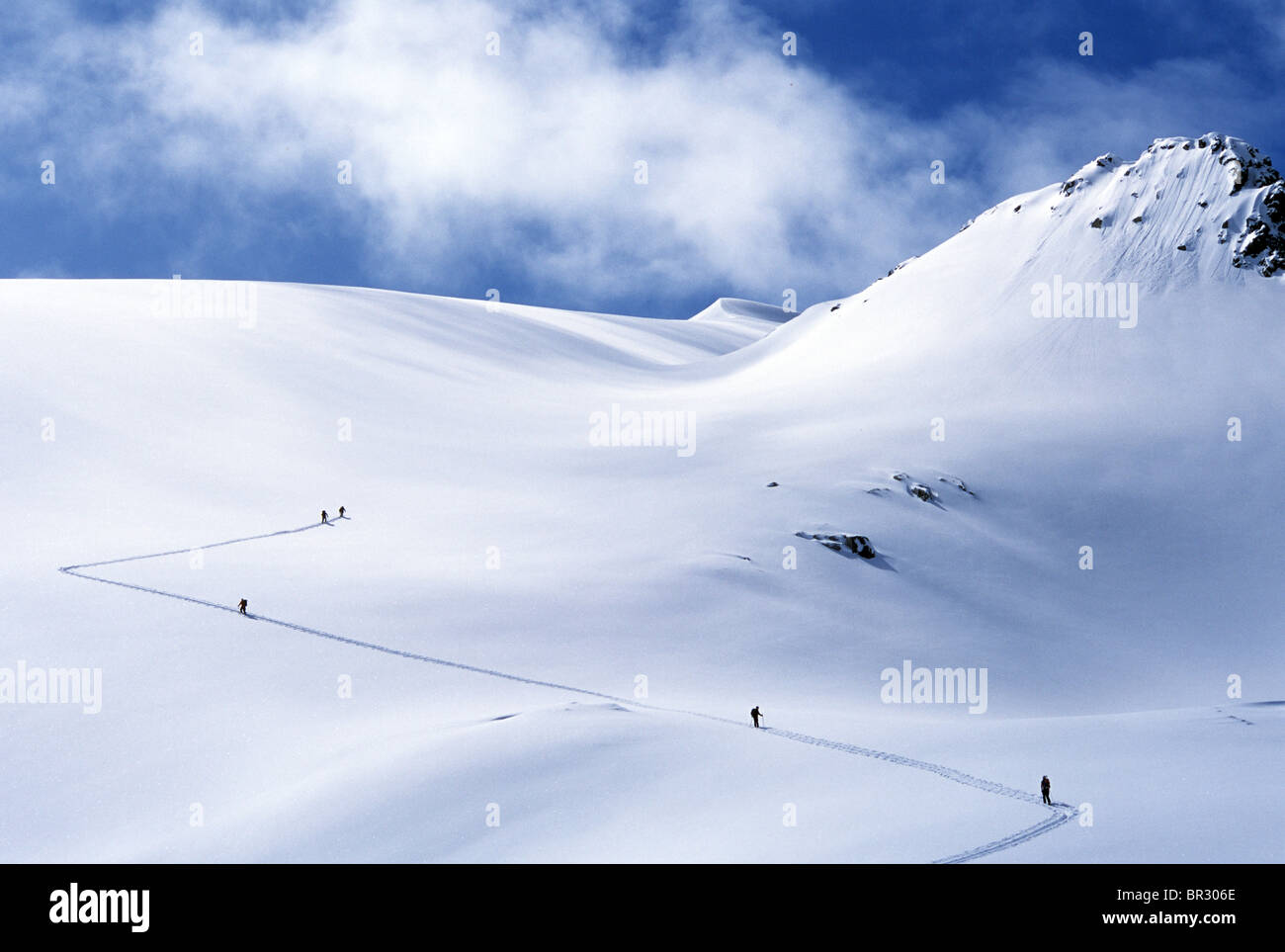 Backcountry skiers ascendng steep slope onto glacier Stock Photo - Alamy