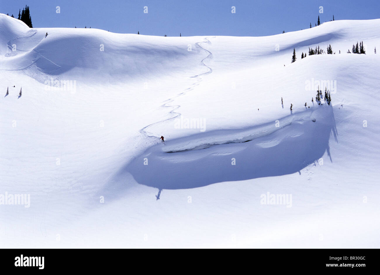 Skier skiing large open slope and off small cliff Stock Photo - Alamy