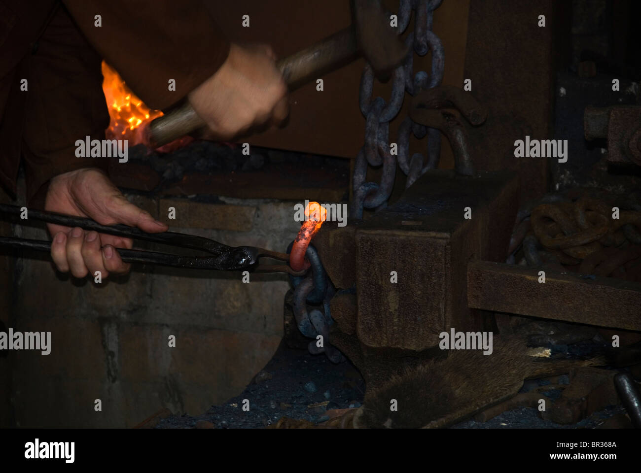 A chain maker brings his hammer down as he shapes the next link to the ...