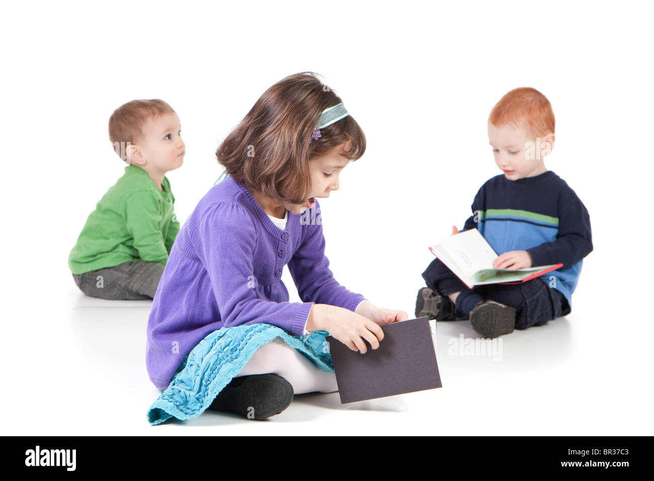 Three kids sitting on floor and reading books. Isolated on white with ...