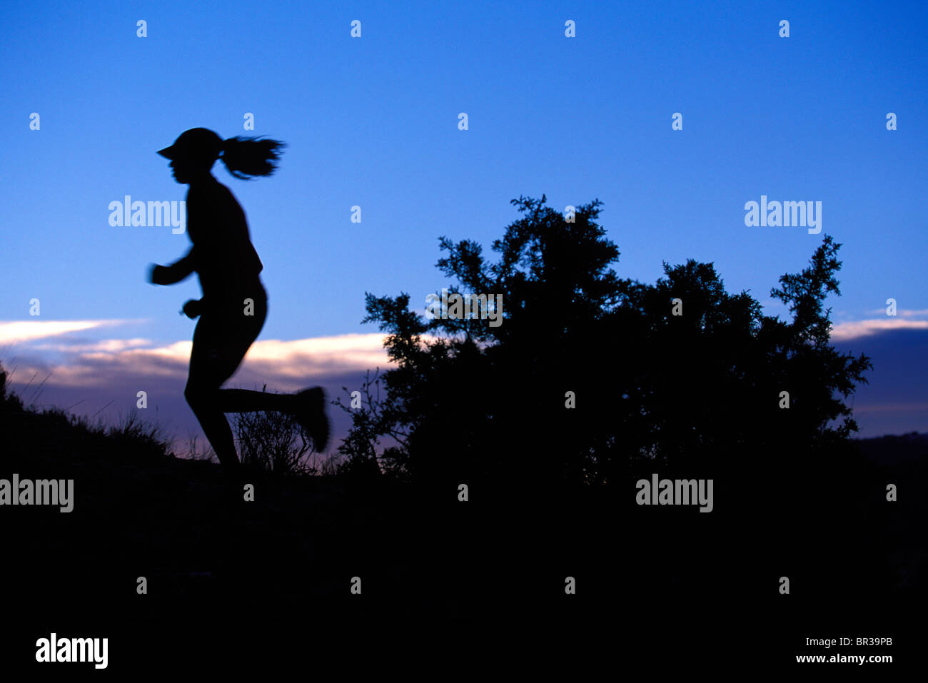 Silhouette of a female runner running in the mountains Stock Photo - Alamy