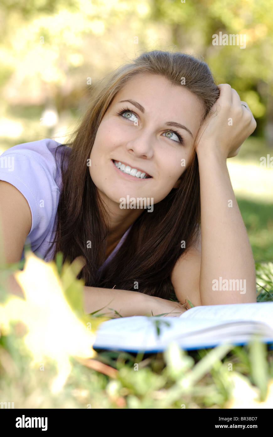 Beautiful young female student takes rest with book outdoors Stock ...