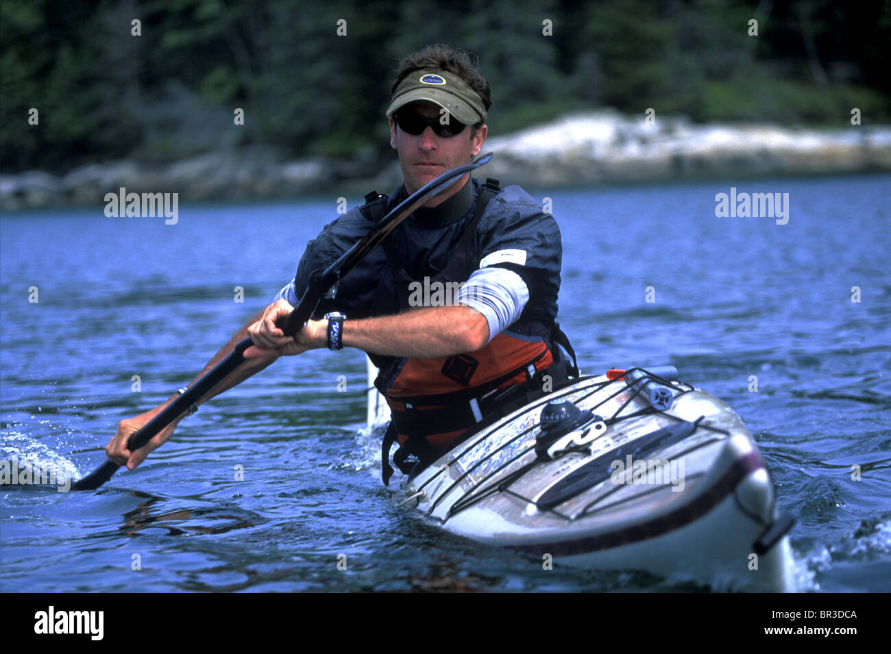 A man paddles his sea kayak near Thief Island on Muscungus Bay, Maine ...