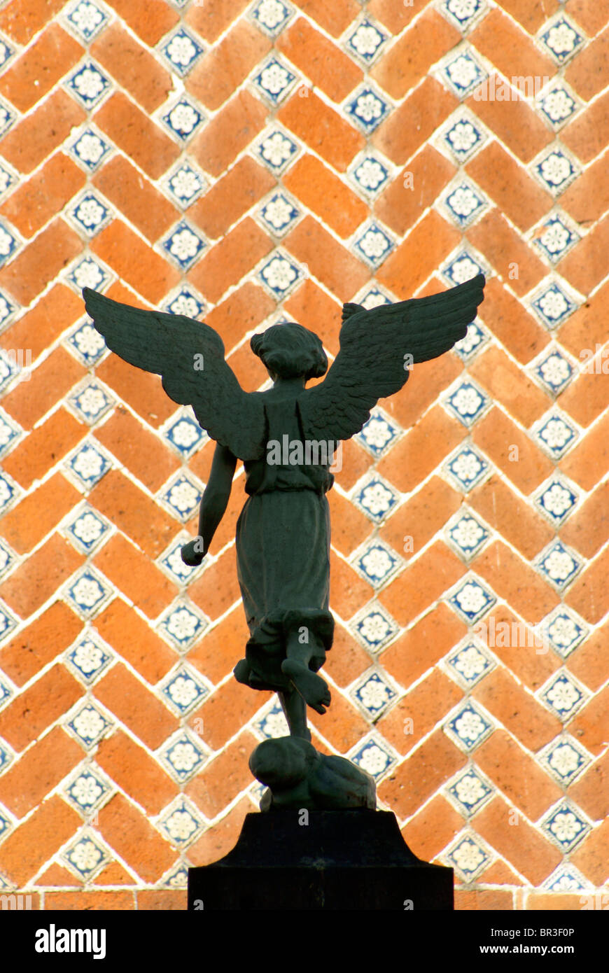 Winged angel statue with colorful Talavera tiled facade in background ...