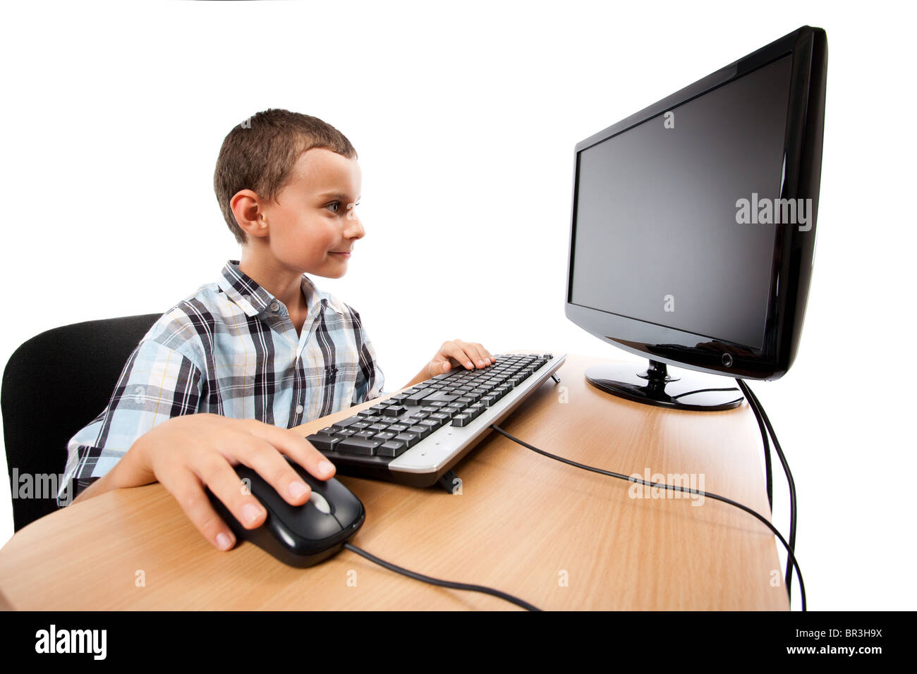Cute schoolboy at his computer. The monitor can be used as copyspace ...