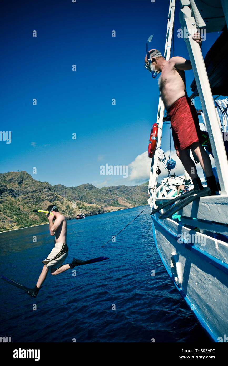 Two men jumping off the side of a boat Stock Photo - Alamy