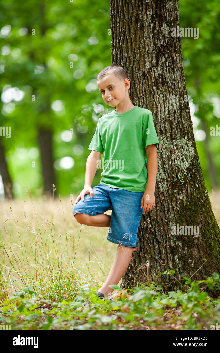 Portrait of a kid in the forest, leaning against a tree Stock Photo - Alamy