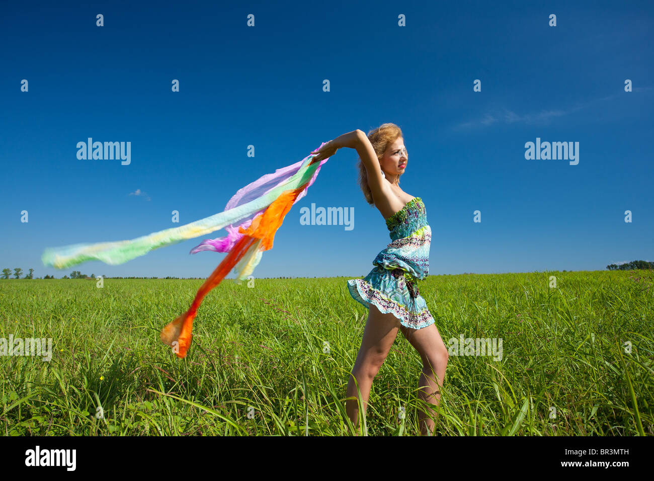 Beautiful blonde woman with colorful scarf in the wind, motion blur ...