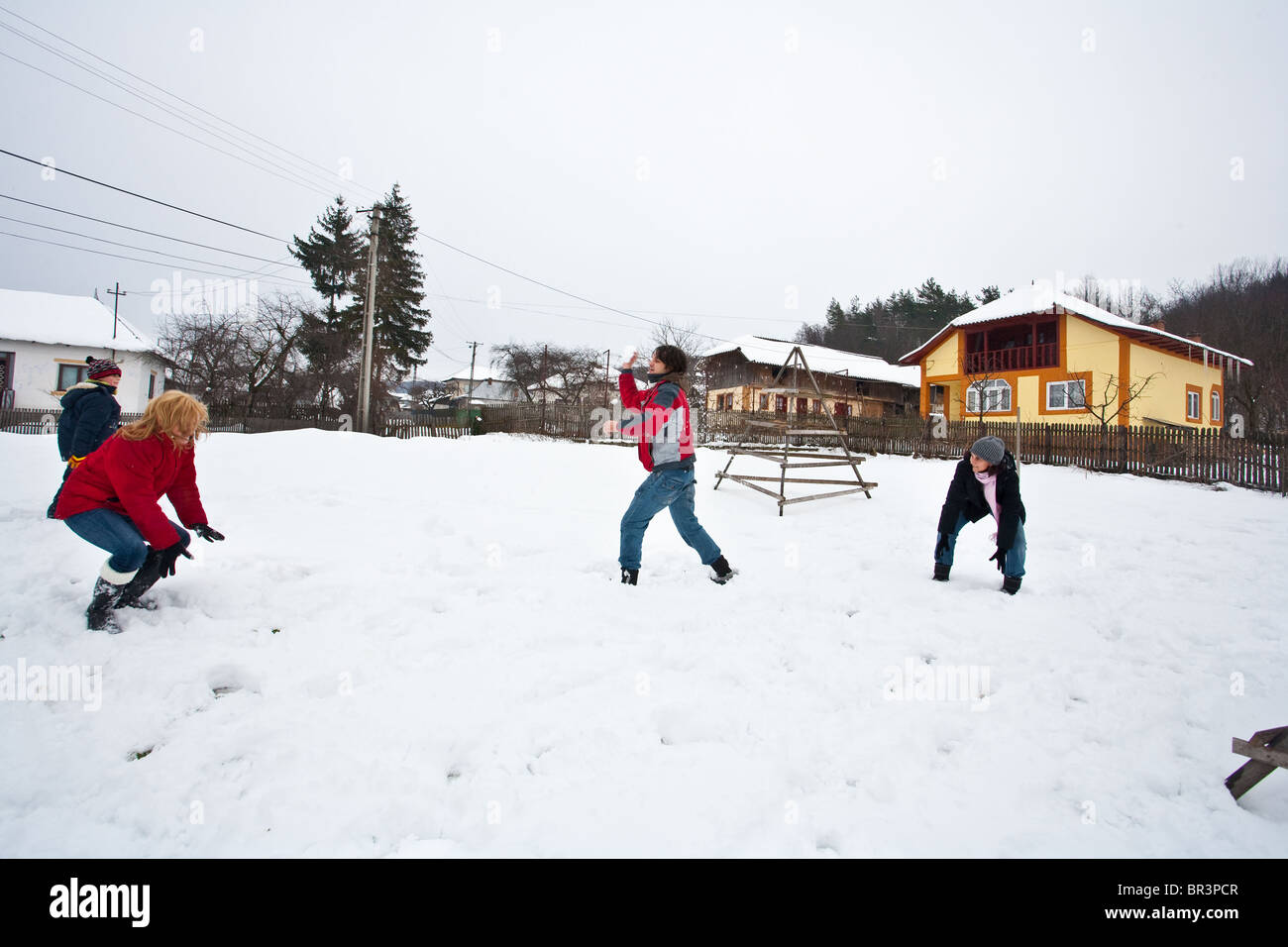 Young family having fun with a snowball fight during winter holiday ...