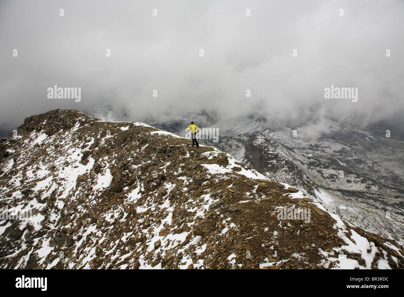 A young man runs along the narrow ridge of a peak in Glacier National ...