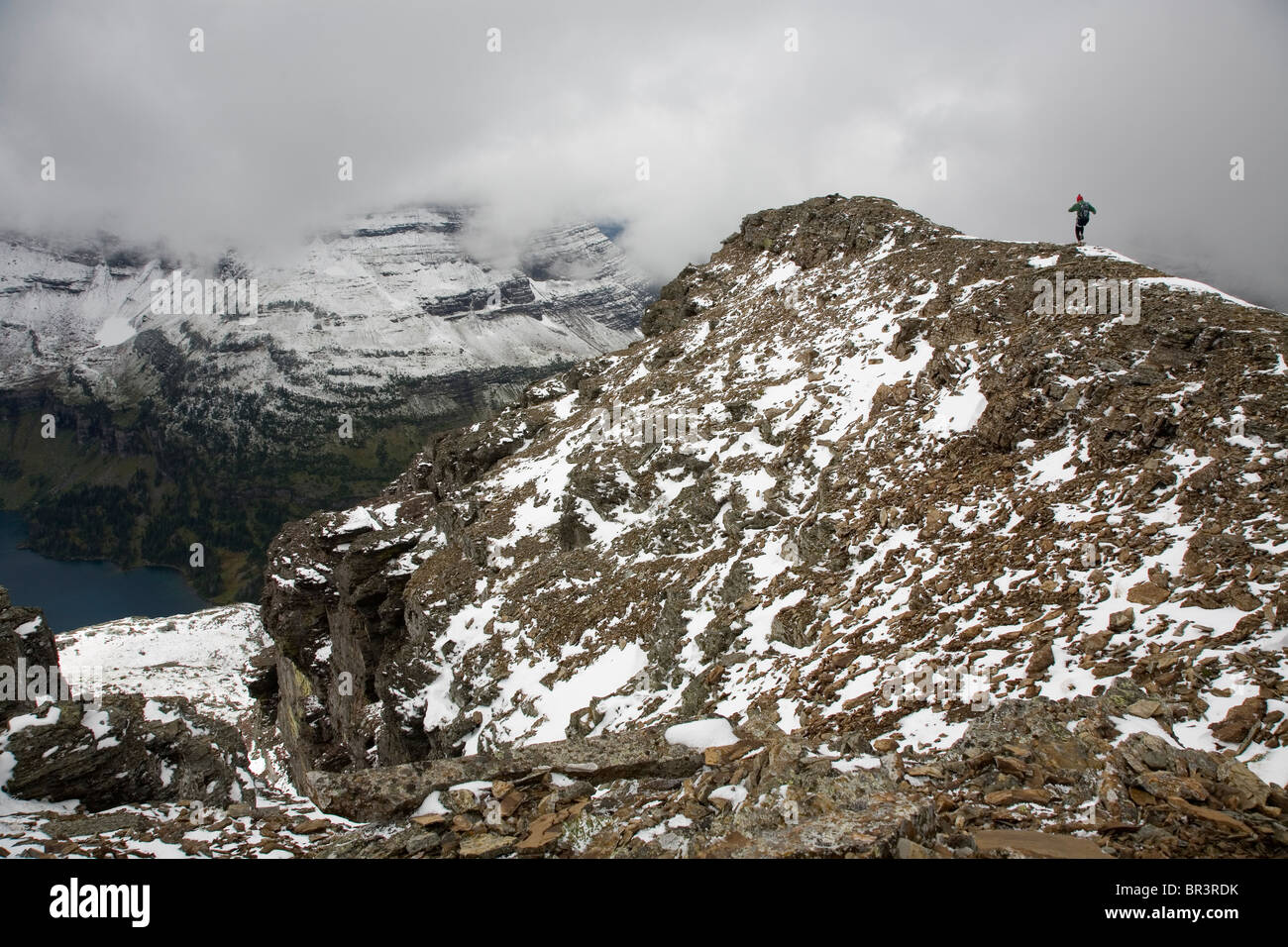 A young woman runs along the narrow ridge of a peak in Glacier National ...