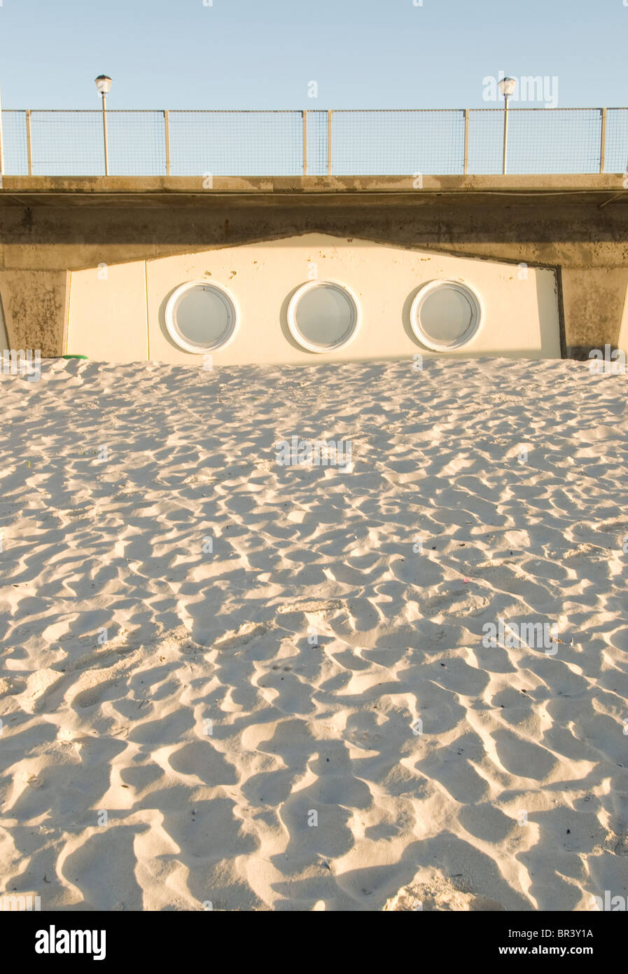 Three portholes looking out below a bridge onto the beach at Muizenberg ...
