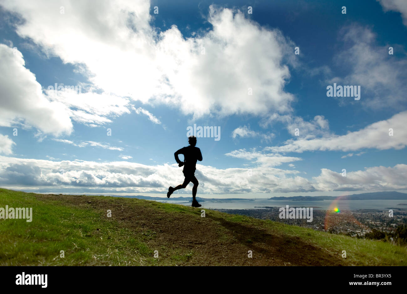 Silhouette of a man trail running above a city Stock Photo - Alamy
