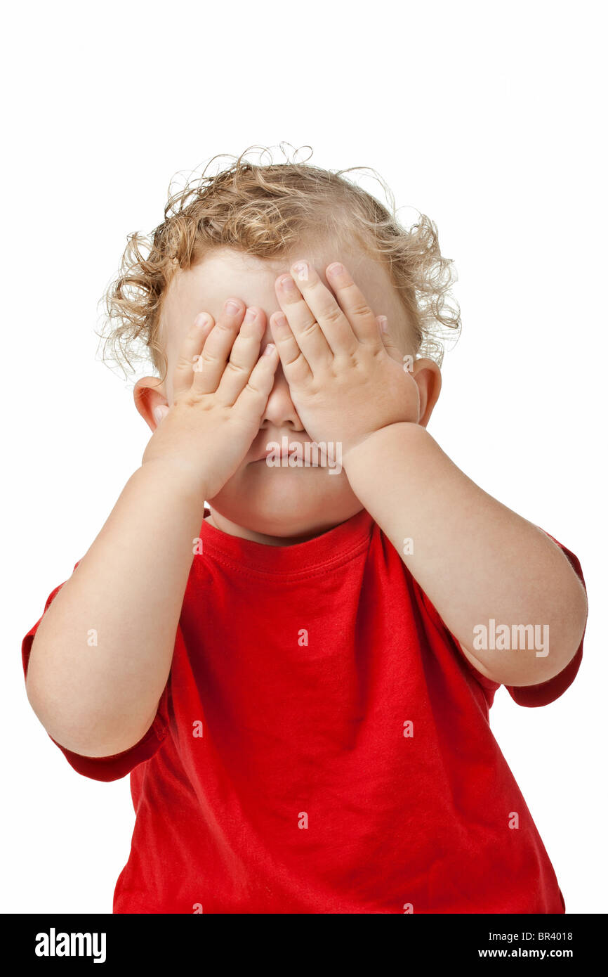 Baby girl covering her eyes with her hands playing peek-a-boo isolated ...