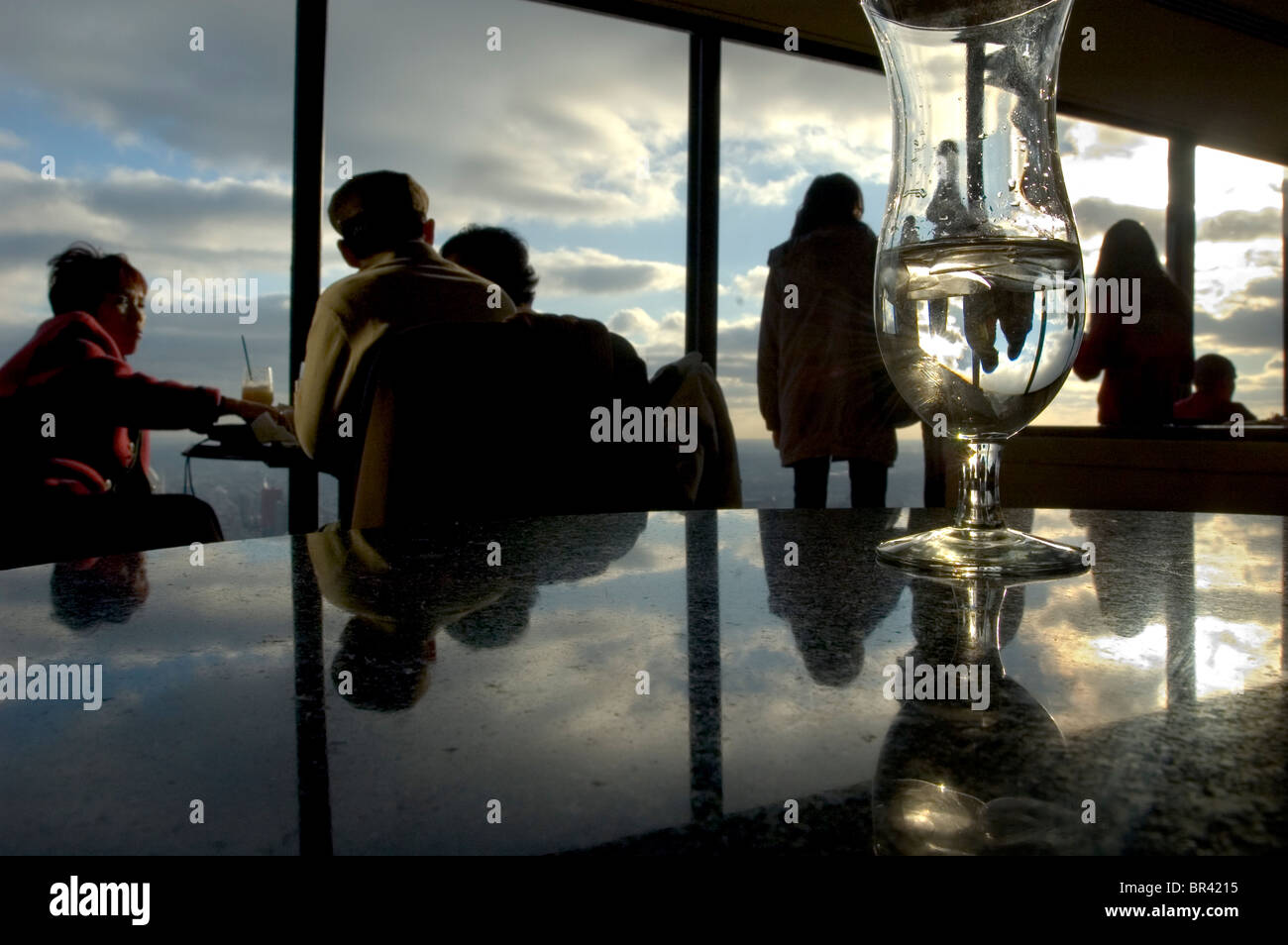 Clouds and people's silhouettes reflect at an observation deck ...
