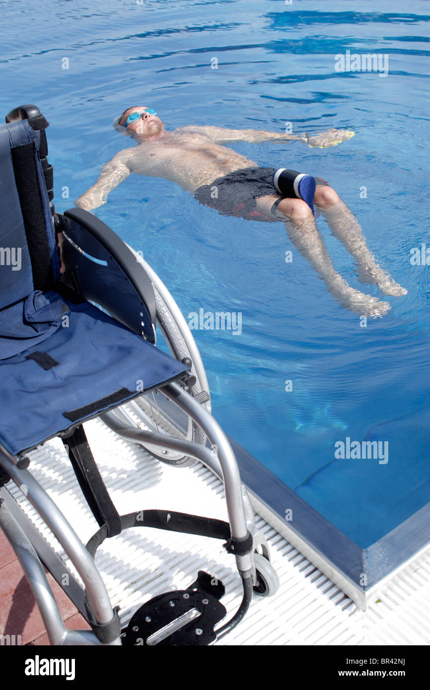 Young, handicapped man, wheelchair user, swimming exercises in a ...