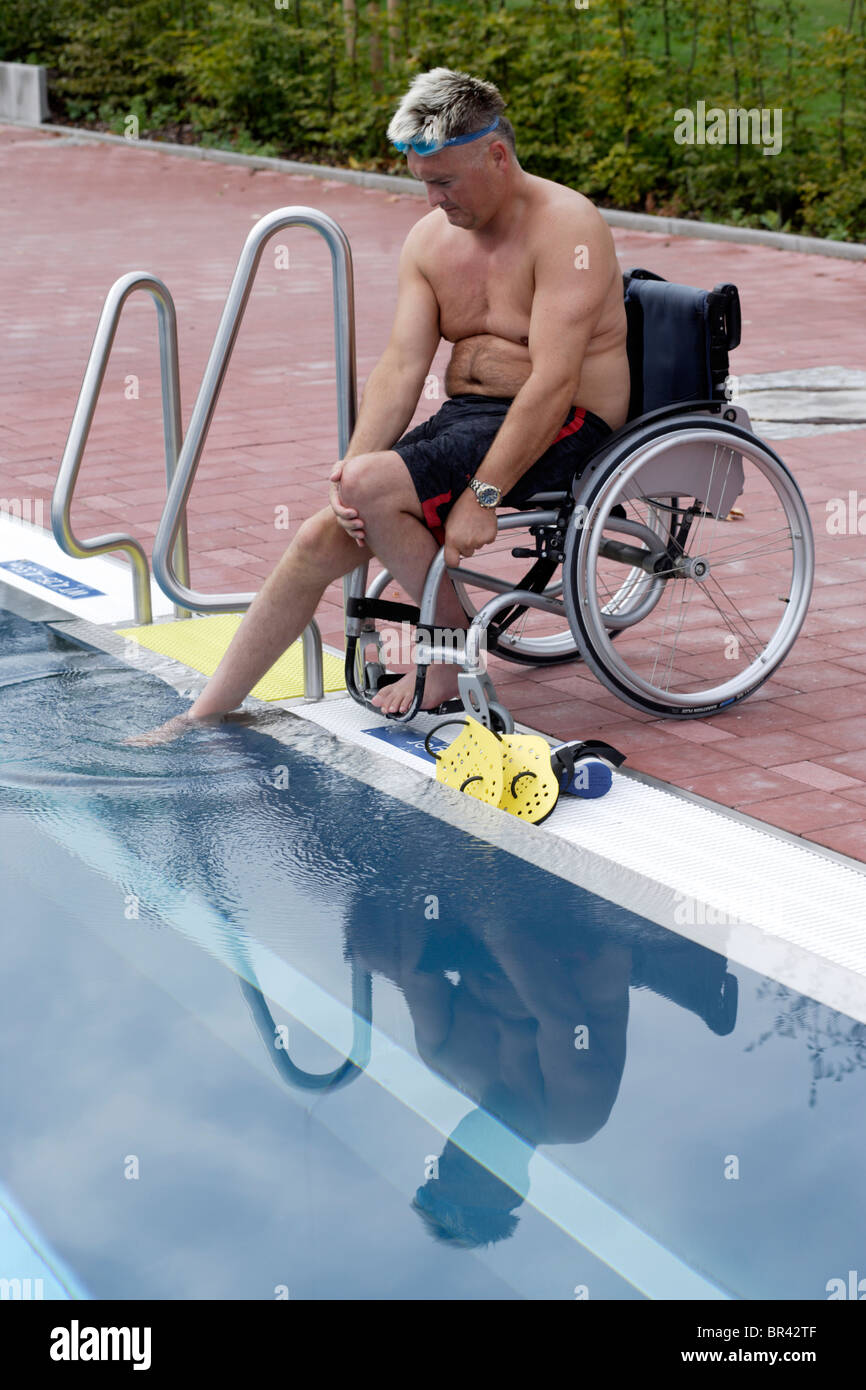 Young, handicapped man in a wheelchair at a swimming pool, stretching ...