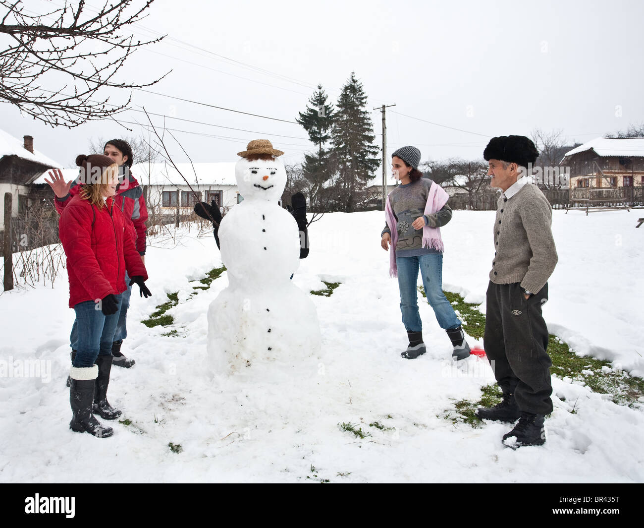 Multi generation family gathering happily together around a snowman, in ...