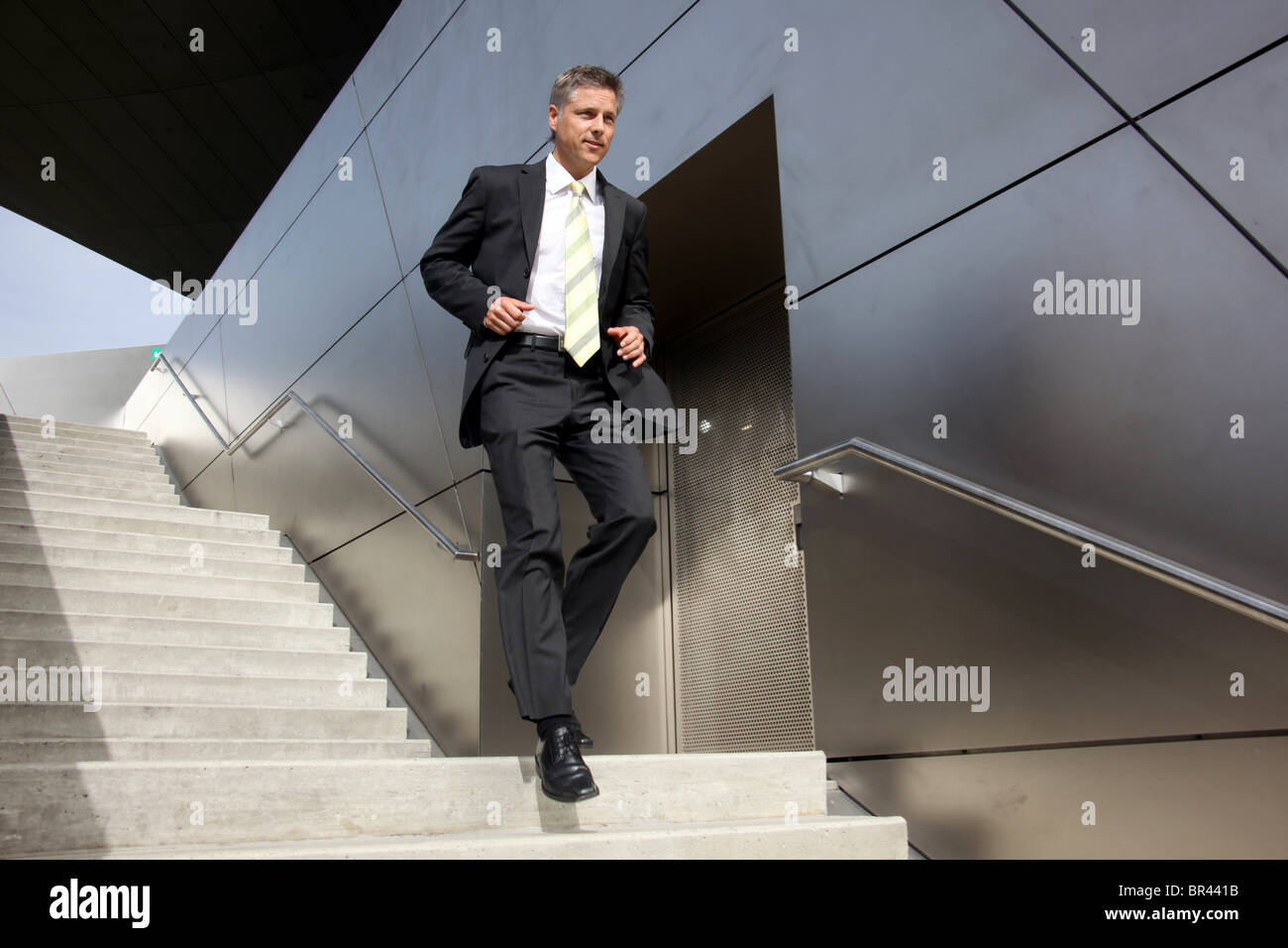 Businessman rushing down stairs Stock Photo - Alamy